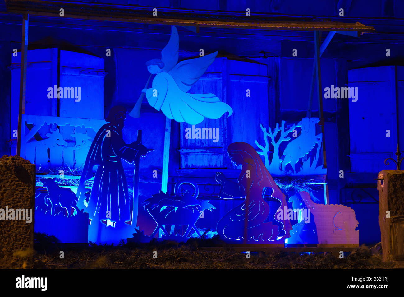 BLUE ILLUMINATED CHRISTMAS NATIVITY SCENE WITH CRIB IN GARDEN DURING ...
