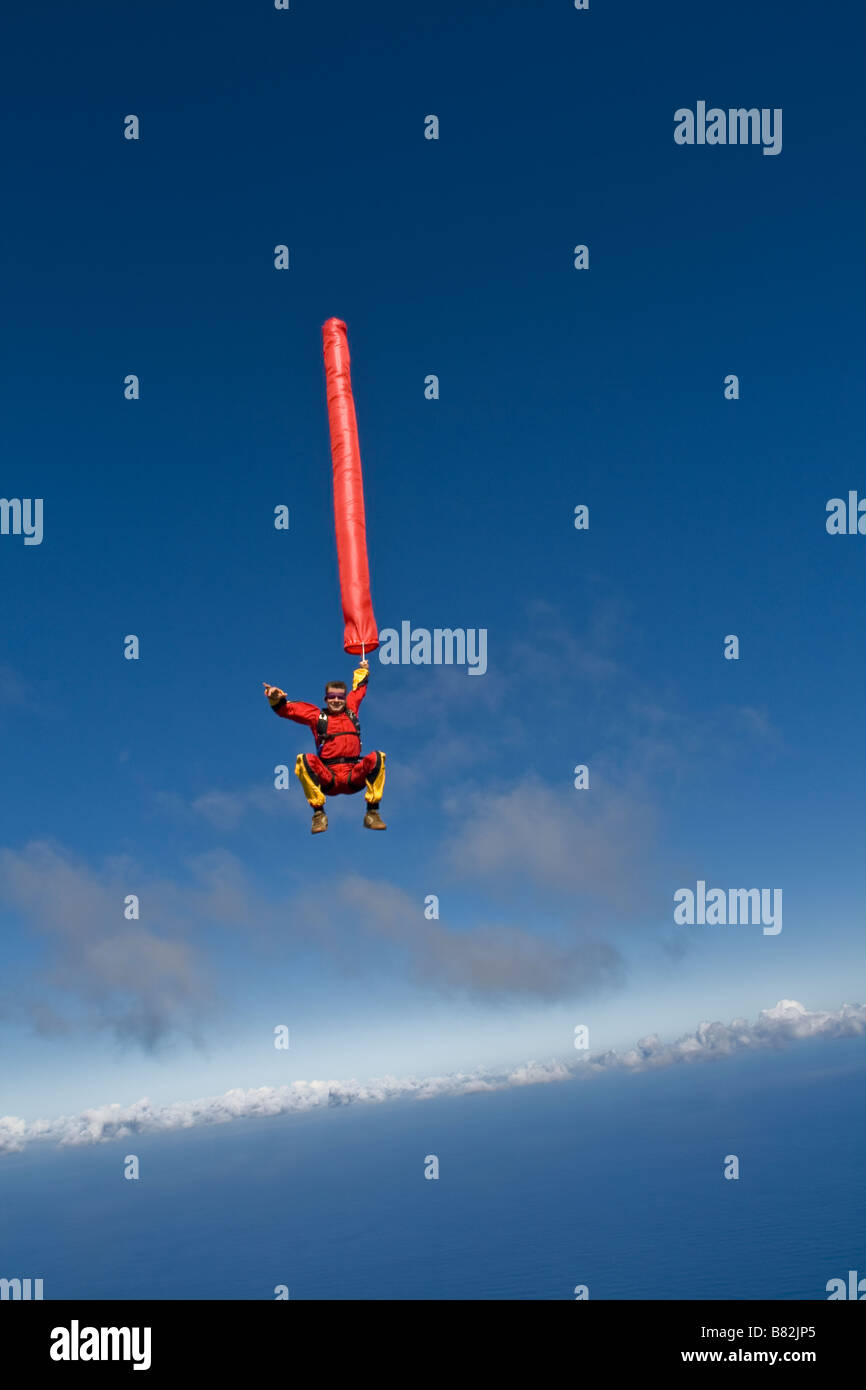 Skydiver having fun in the sky with a colorful tube in his hand and ...