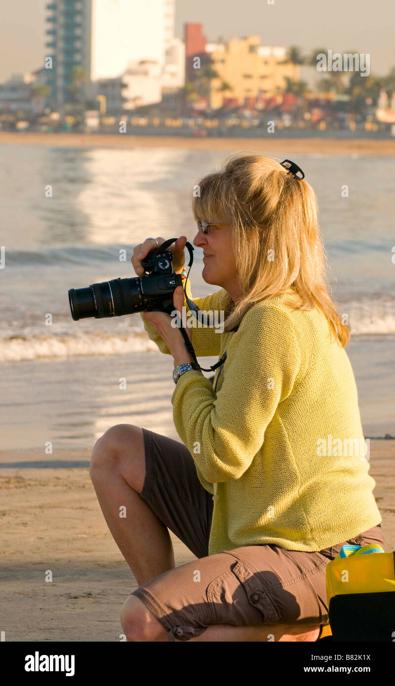 MEXICO SINOLA STATE MAZATLAN Woman photographing Pelicans on Olas Altas ...