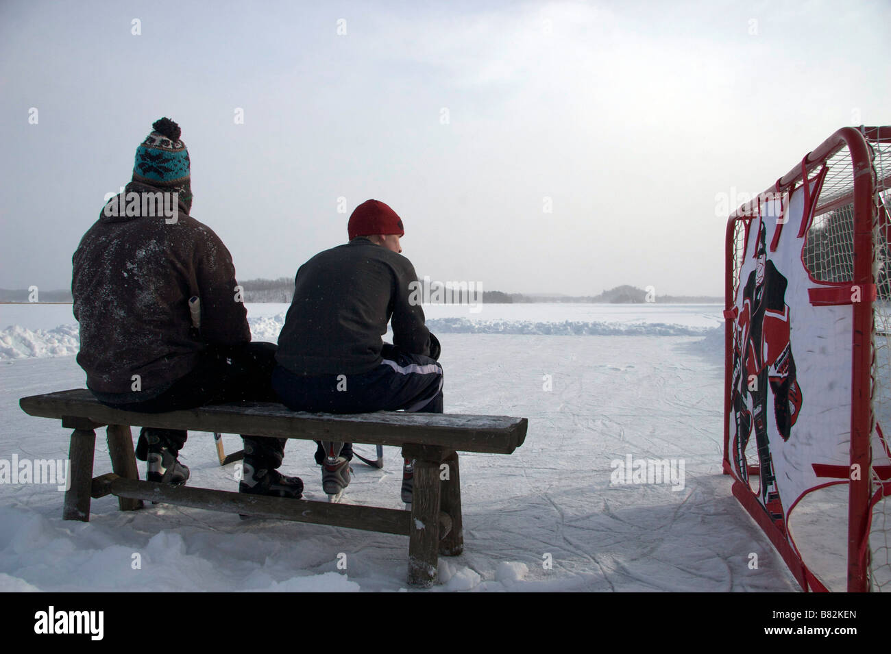 Two guys sitting on bench on lake ice skate rink next to goal Stock ...
