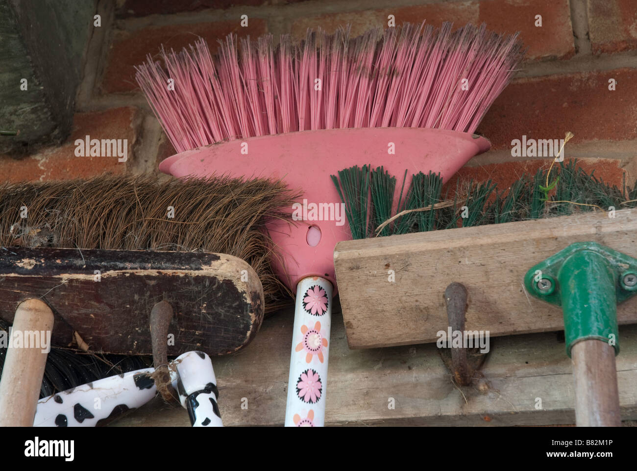 Collection of household brooms hanging up on the wall Stock Photo - Alamy