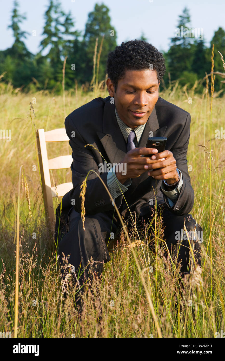 A business man sitting on a chair in a field working with his ...