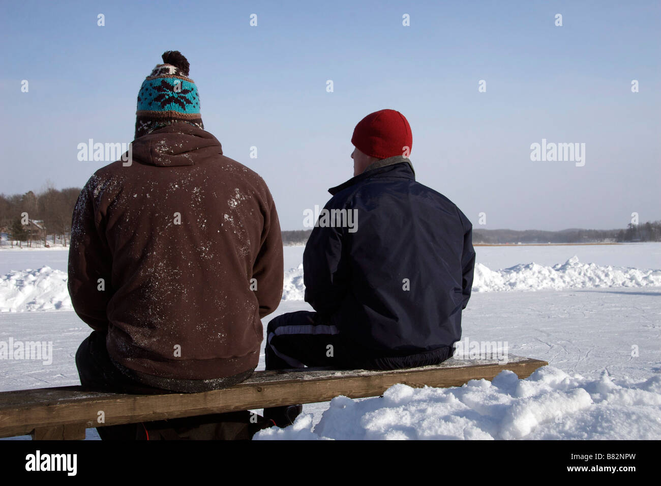 Two guys sitting on bench next to ice skating rink Stock Photo - Alamy