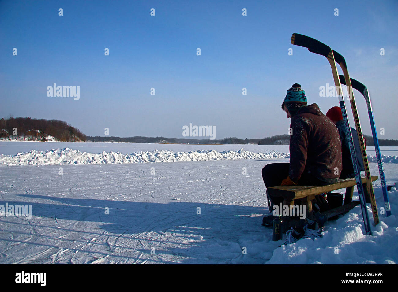 Two guys sitting on bench next to ice skating rink Stock Photo - Alamy