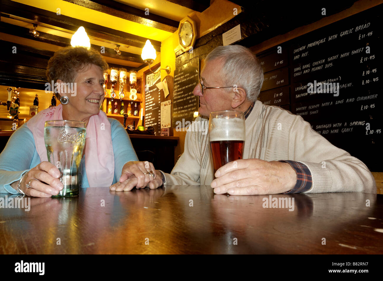 An older couple holding hands and talking in a pub Stock Photo - Alamy