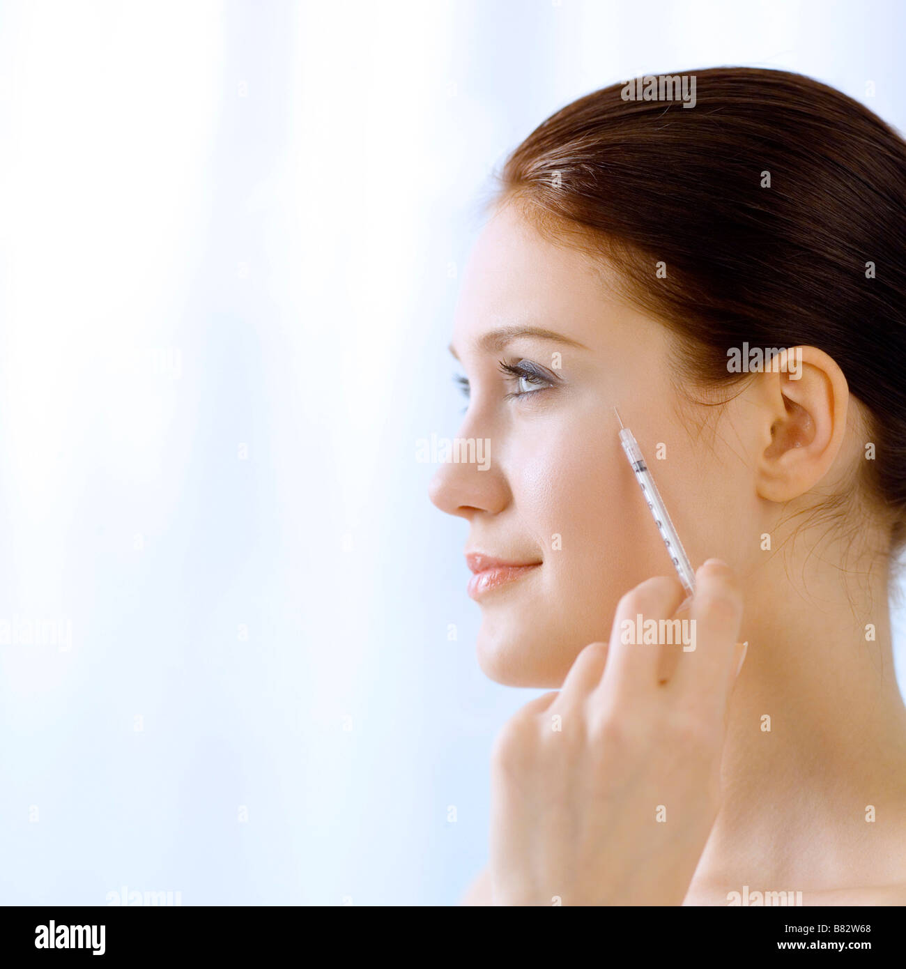 Portrait of young woman holding syringe near face side view Stock Photo ...