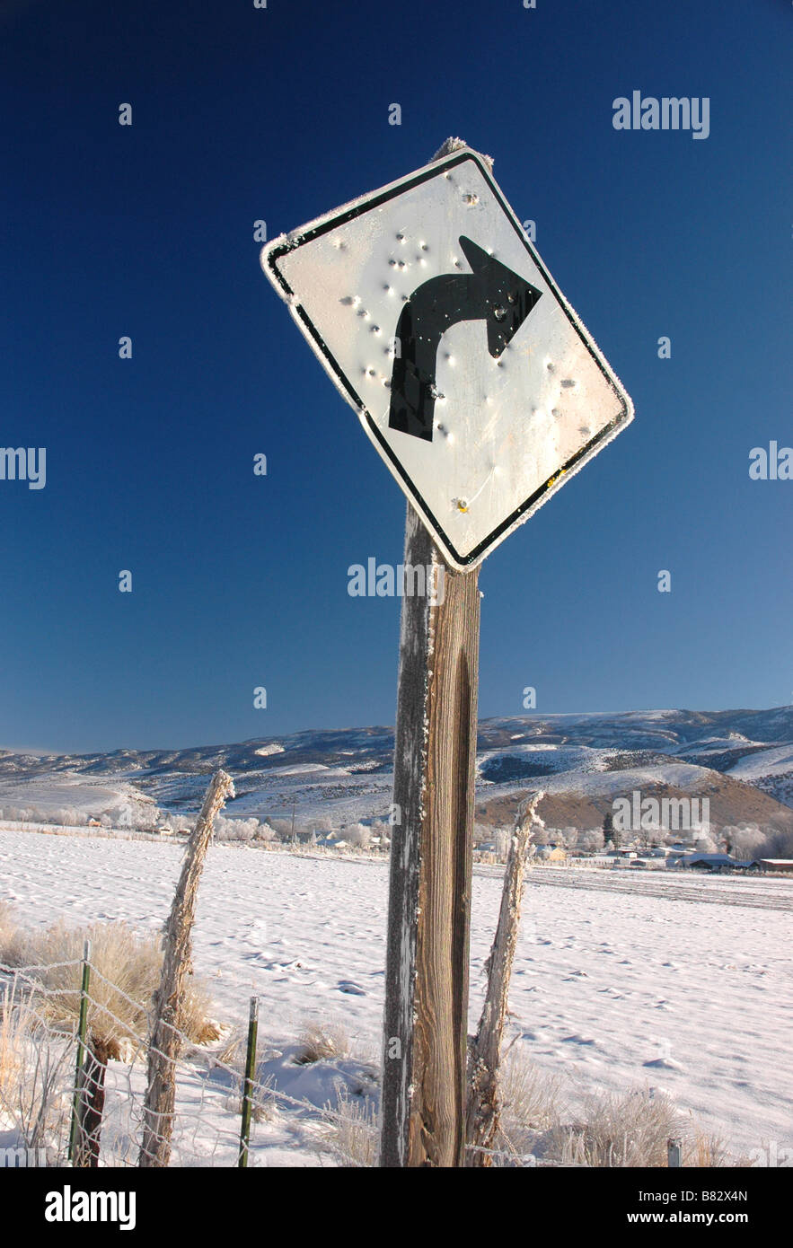 A sharp turn sign with bullet holes in rural Utah Stock Photo - Alamy