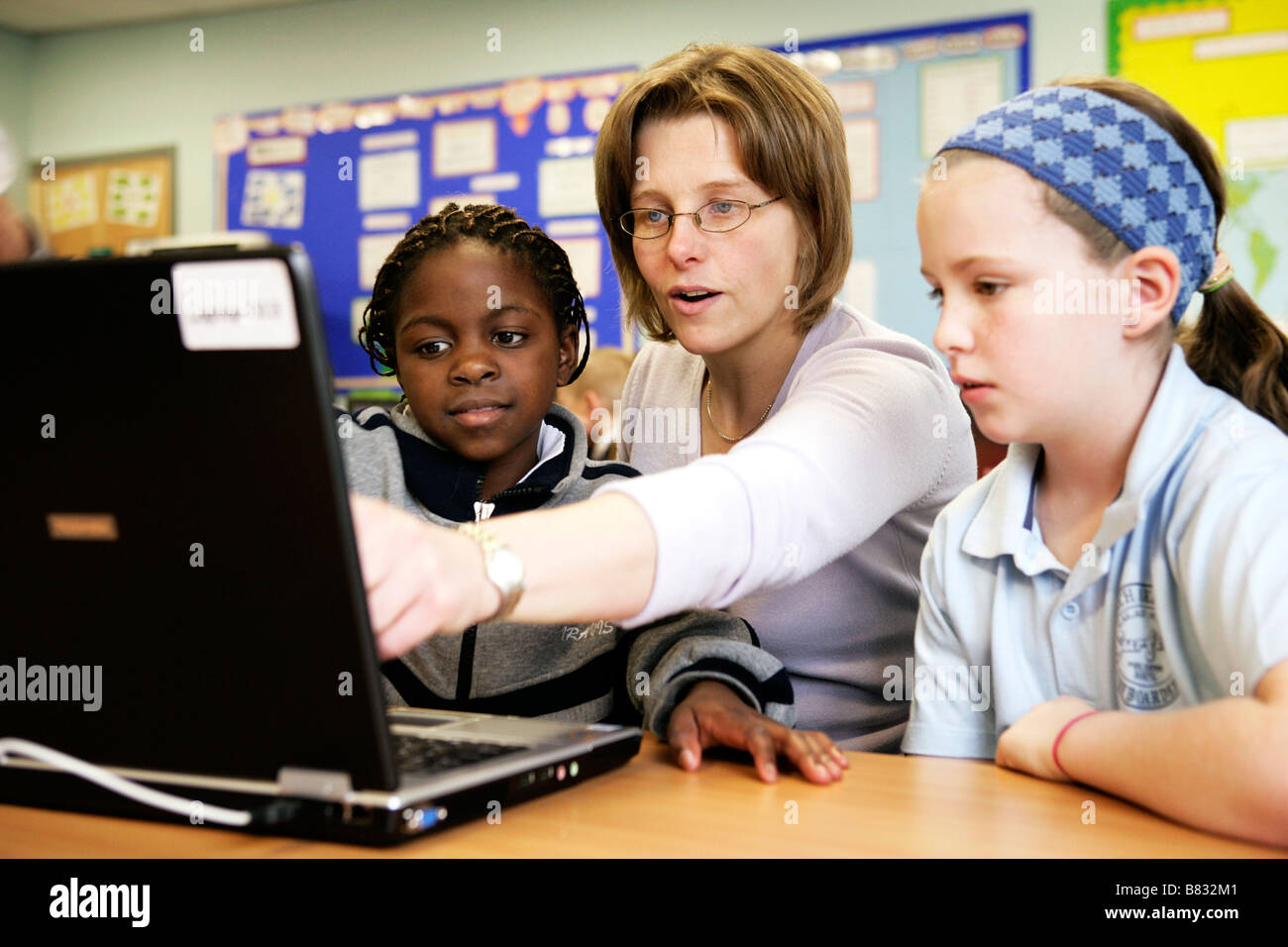 teacher working with primary school pupils on laptop computer Stock ...