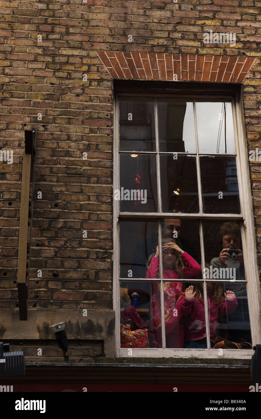 family including children gaze out of London window onto street below ...