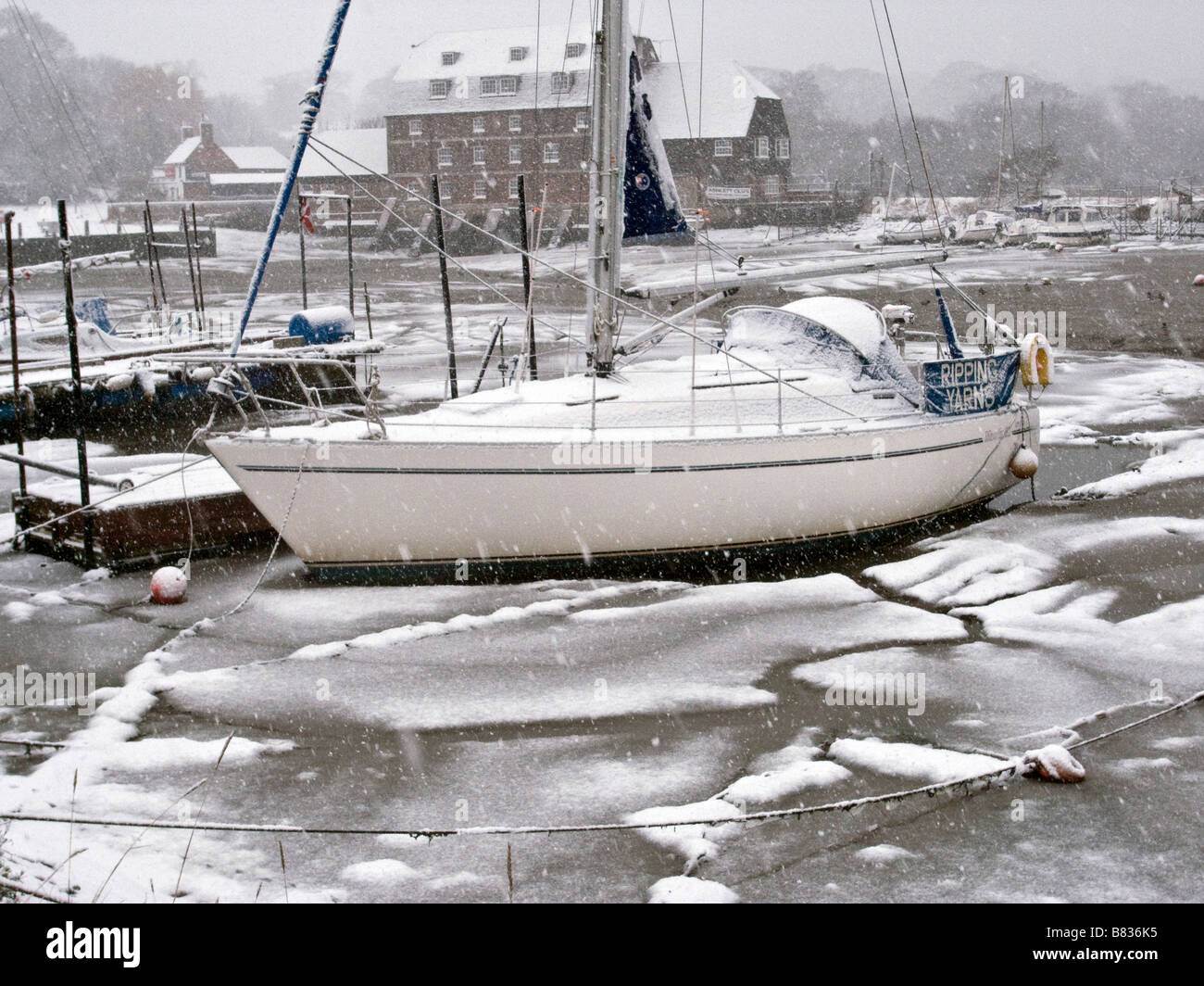 Snow covered yacht along side pontoon at low tide while snowing Stock ...