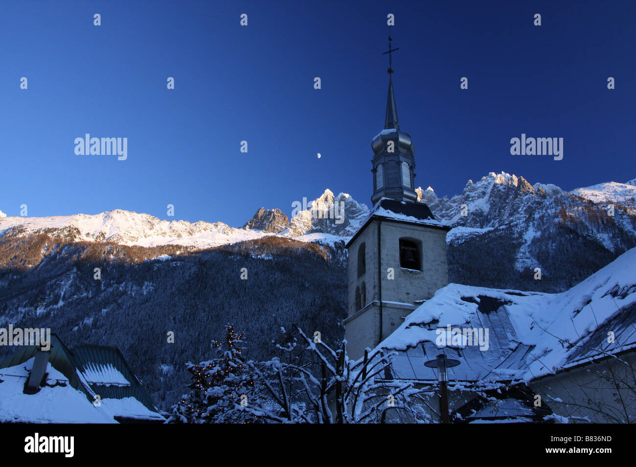 Church in Chamonix Mont Blanc, France, covered in snow with the Alps in ...