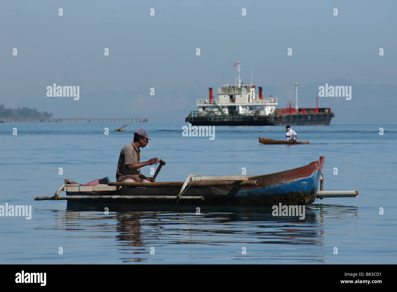 An outrigger canoe in Dili harbor Timor Leste and an inter-island ferry ...
