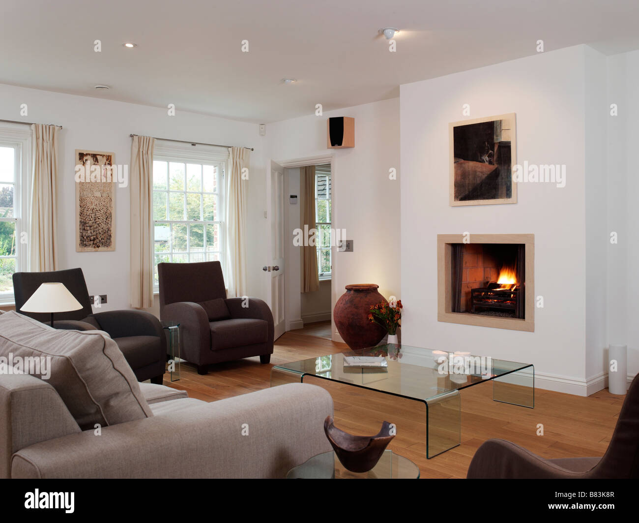 modern living room with neutral decor and open lit modern fireplace and ...