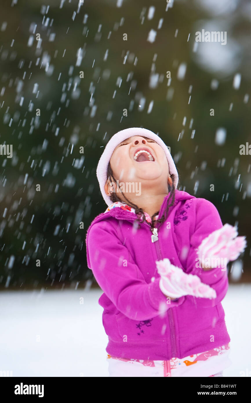 A beautiful young girl having fun playing in the snow and catching ...