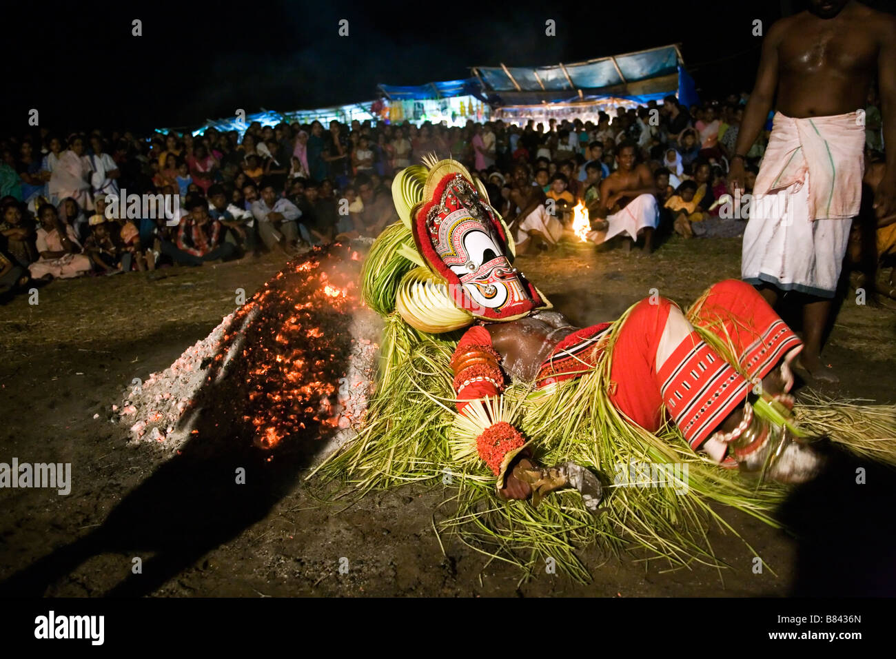 A theyyam performing an ancient trance ritual at night by lying on a ...