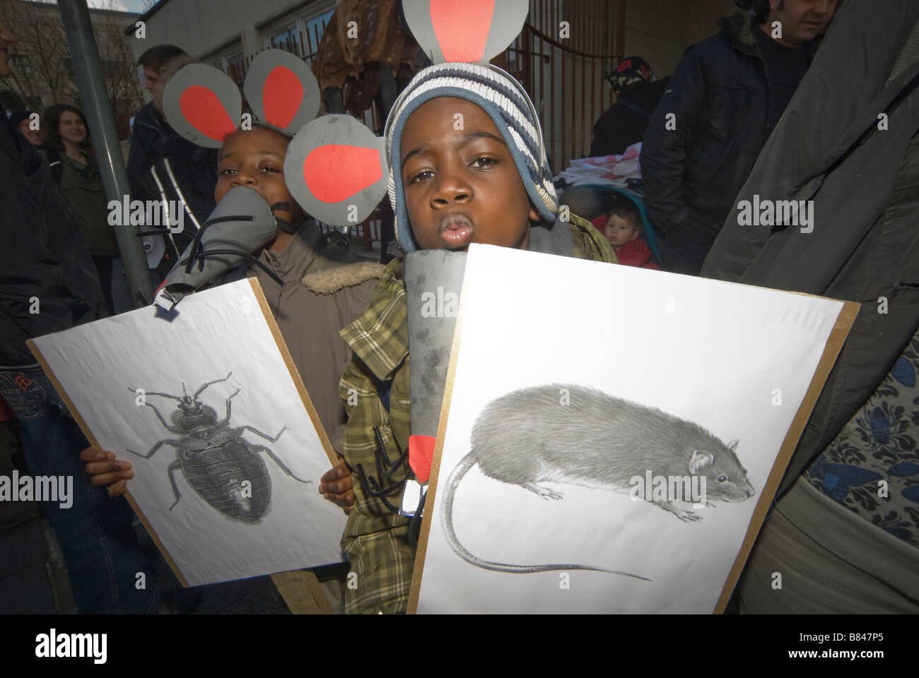 Kids living in temporary hostel dressed as mice show placards with ...