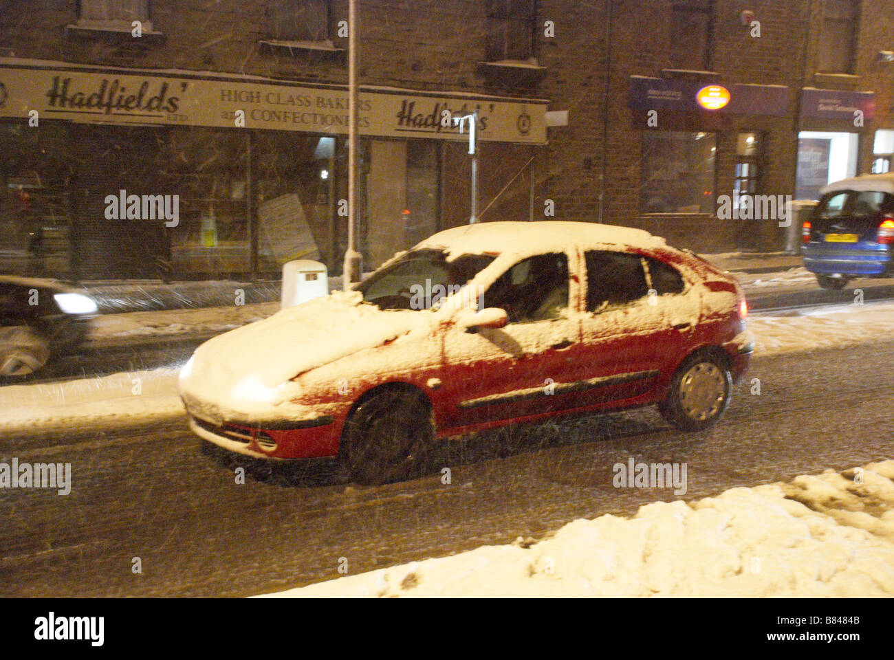 Red car in a snow storm UK Stock Photo - Alamy