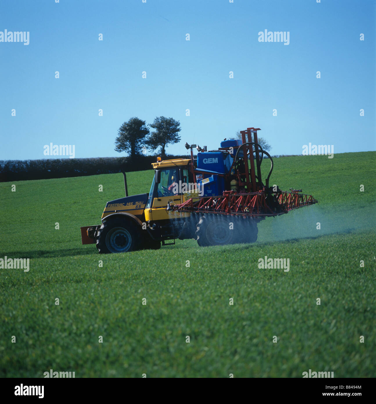 Fastrac tractor and mounted Gem sprayer spraying a young barley crop in ...