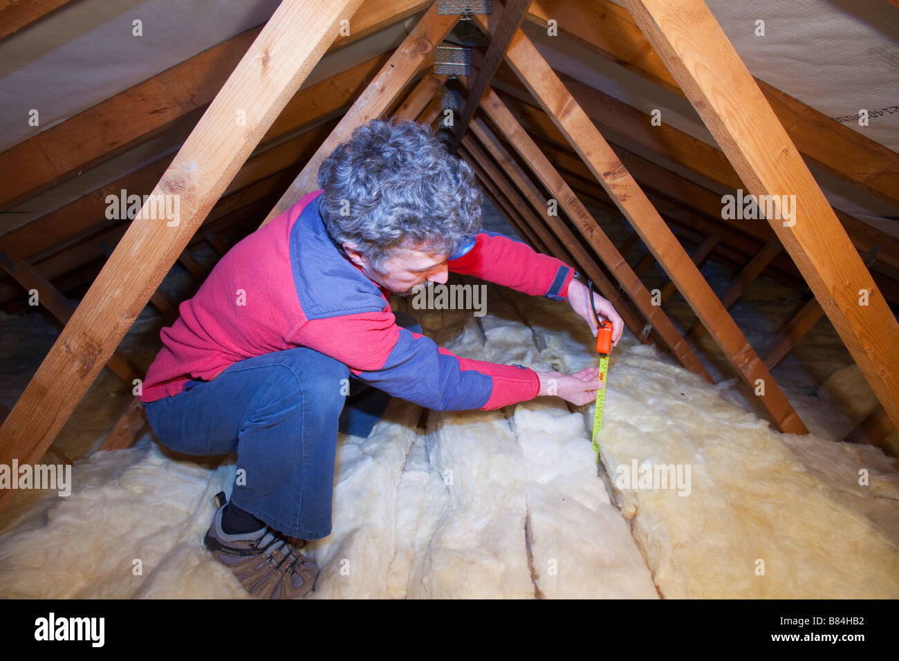 a man measuring loft insulation Stock Photo - Alamy