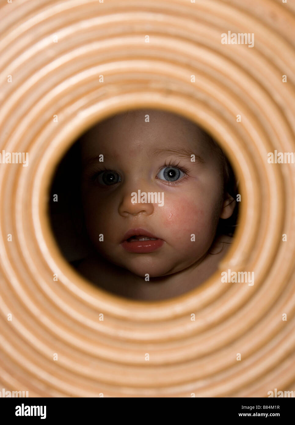 A baby girl looking through a laundry basket lid Stock Photo - Alamy