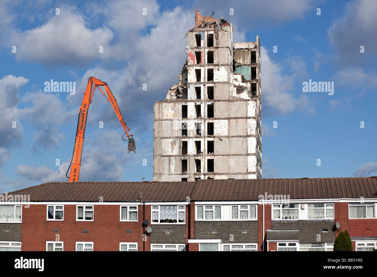 A residential tower block being demolished behind a row of houses in ...