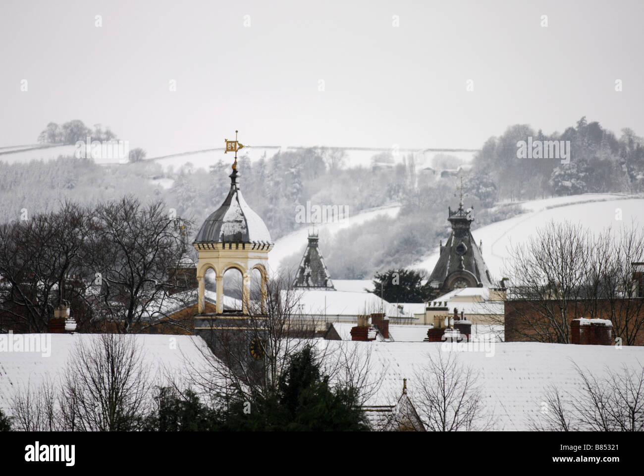 Winter snow Tiverton in Devon. A view across rooftops of the towers ...