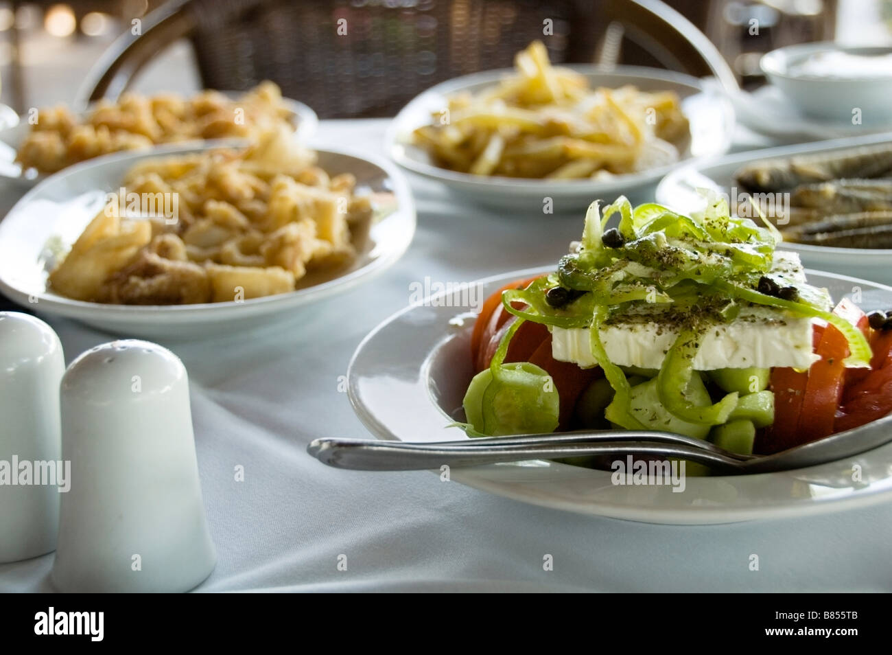 Traditional Greek salad with feta cheese on white plate and table cloth ...