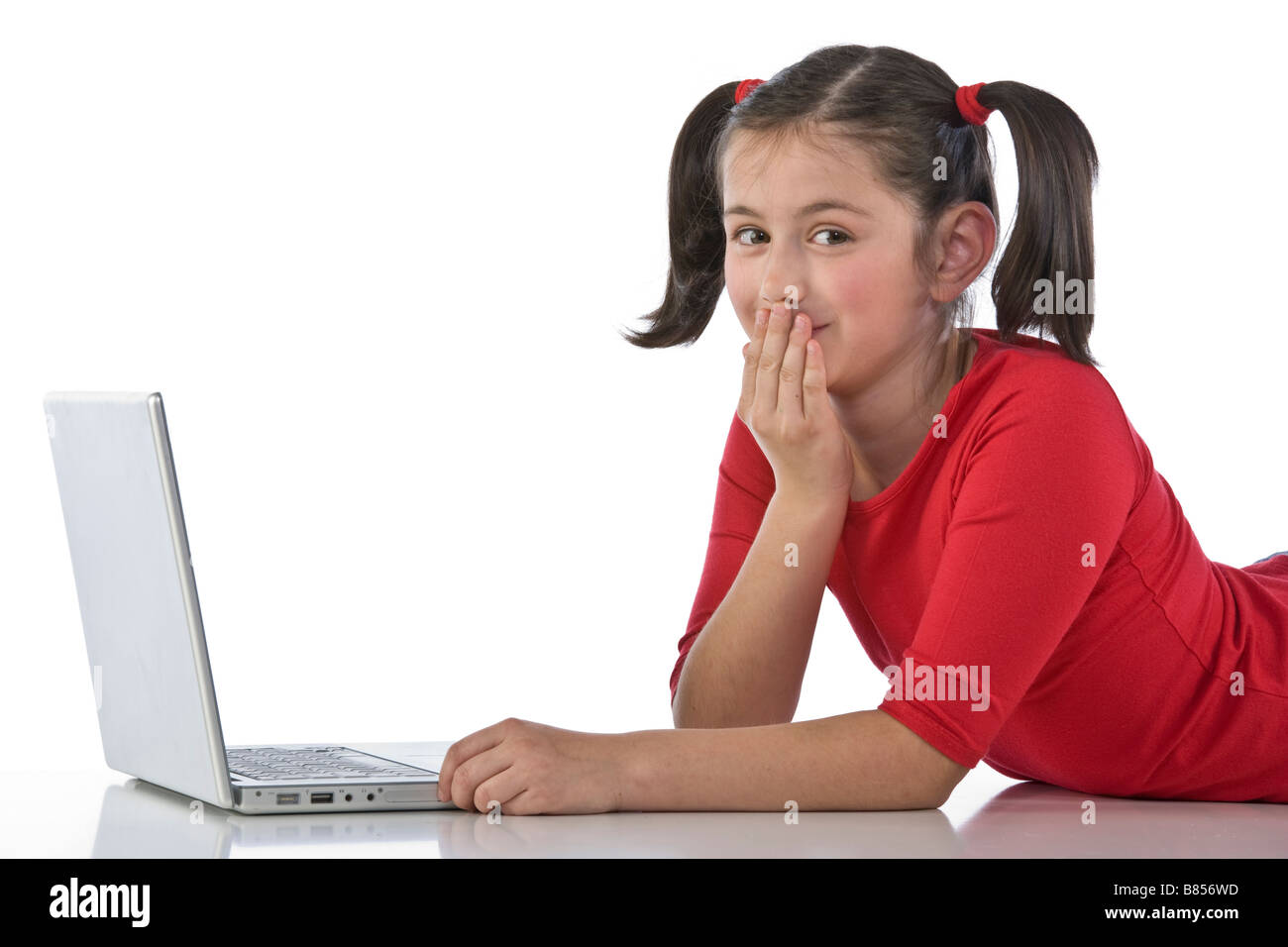 Adorable caucasian little girl lying with laptop Stock Photo - Alamy