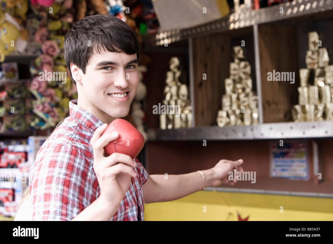 portrait of young man at fun fair throwing ball at cans Stock Photo - Alamy
