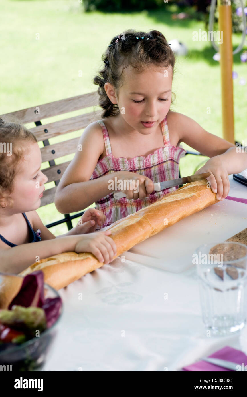 two little sisters sharing bread at table in garden Stock Photo - Alamy