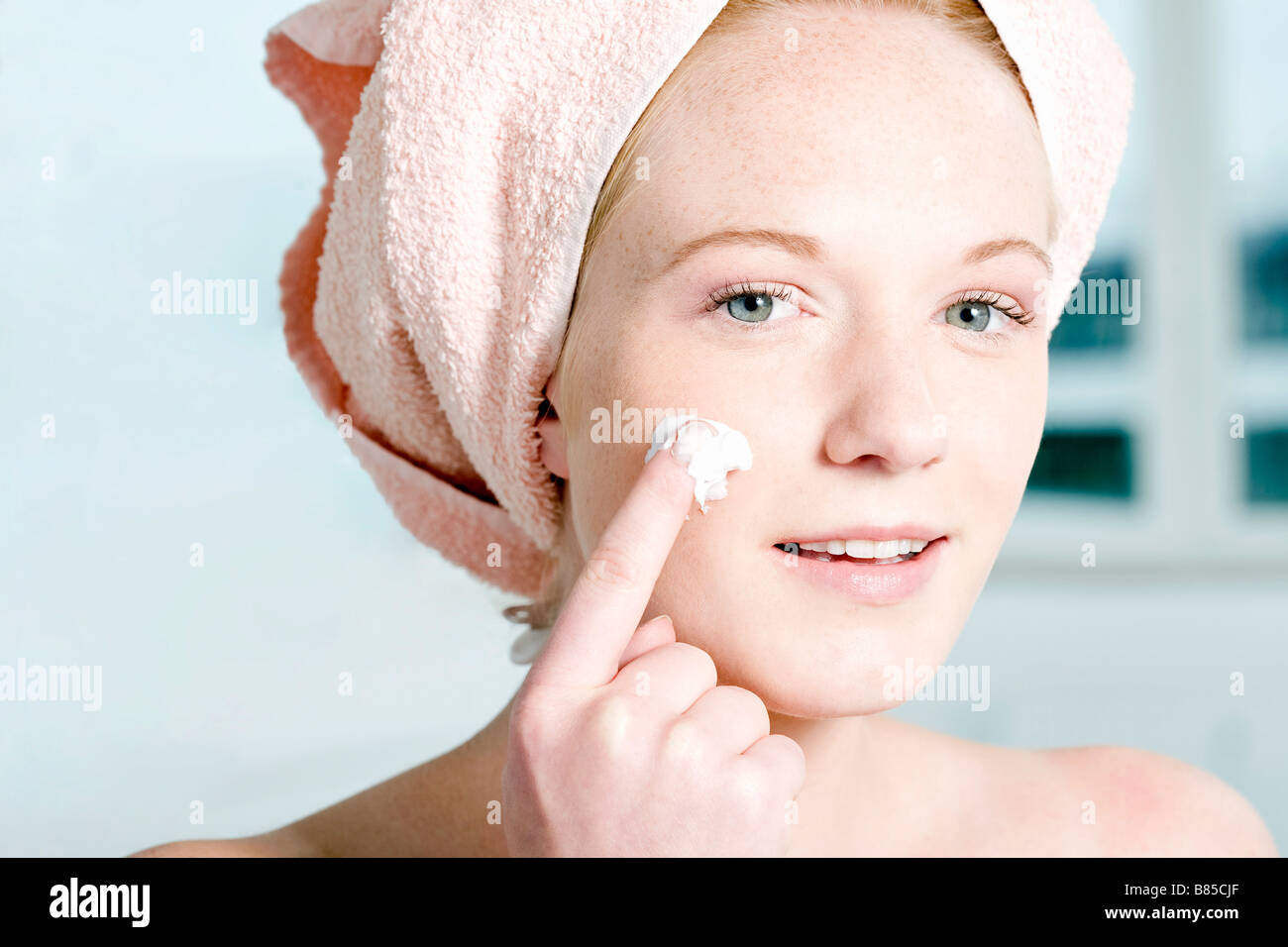 headshot of young woman applying skin cream on face Stock Photo - Alamy