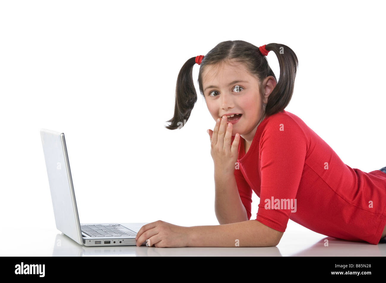 Adorable caucasian little girl lying with laptop Stock Photo - Alamy