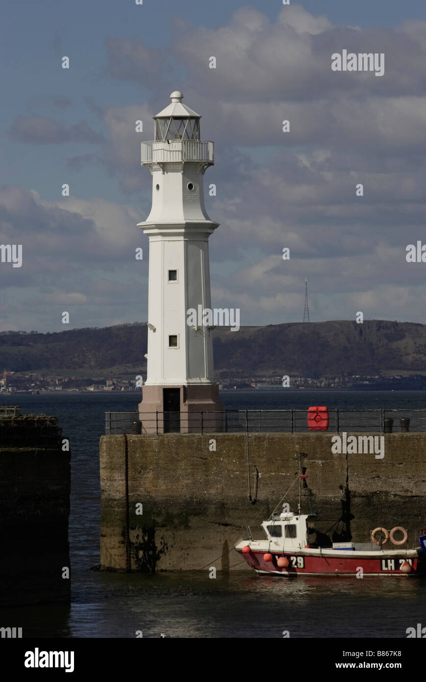 A boat and light house at a harbour Stock Photo - Alamy
