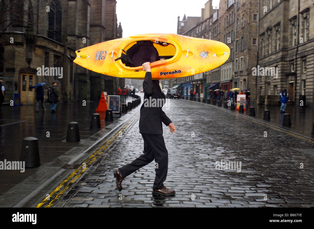 A man carrying a kayak across the road Stock Photo - Alamy