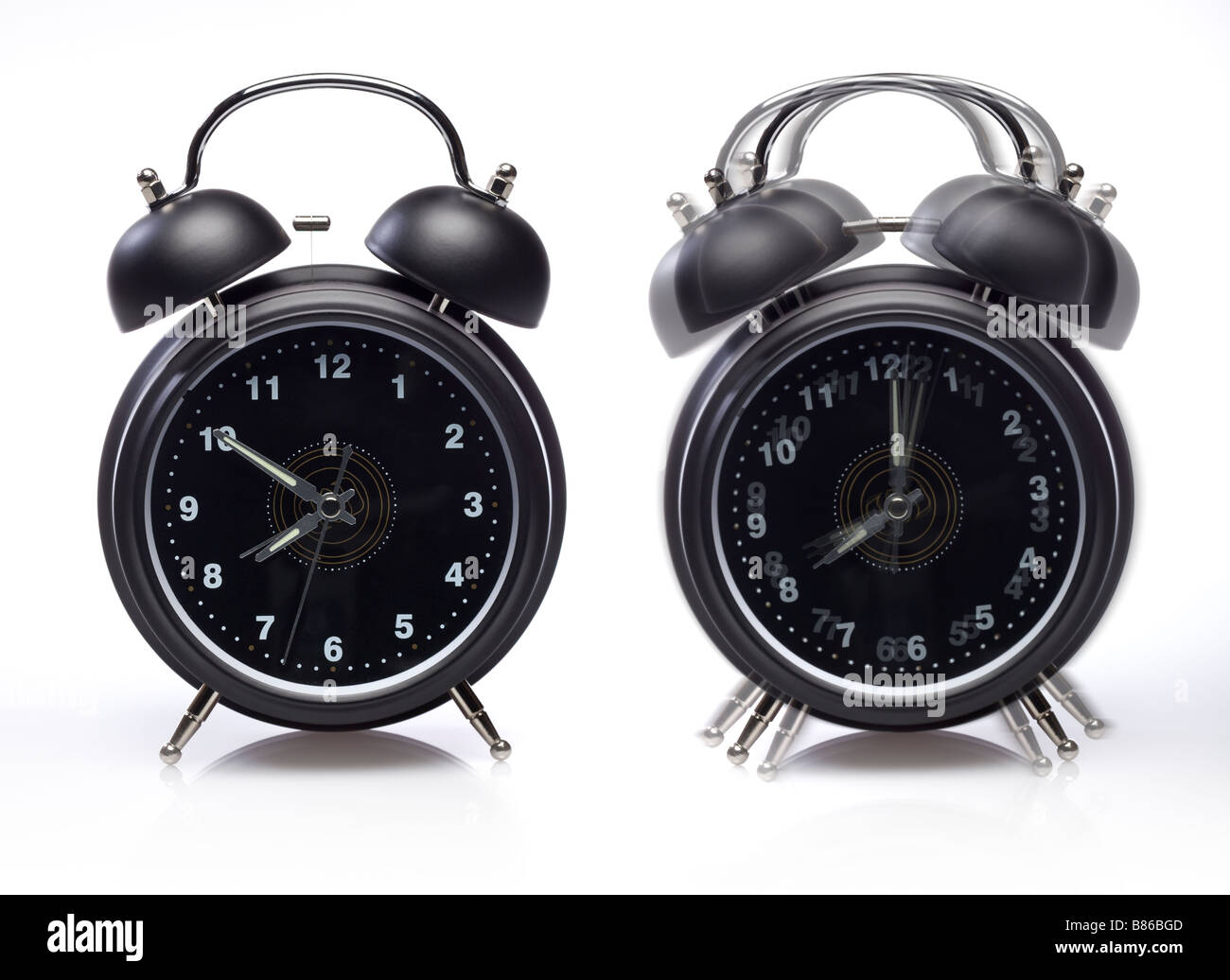 Two retro alarm clocks one still one ringing on white with motion blur ...