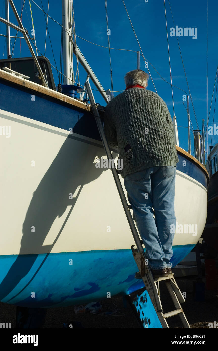 a boat owner carries out old fashioned maintenance and repair work by ...