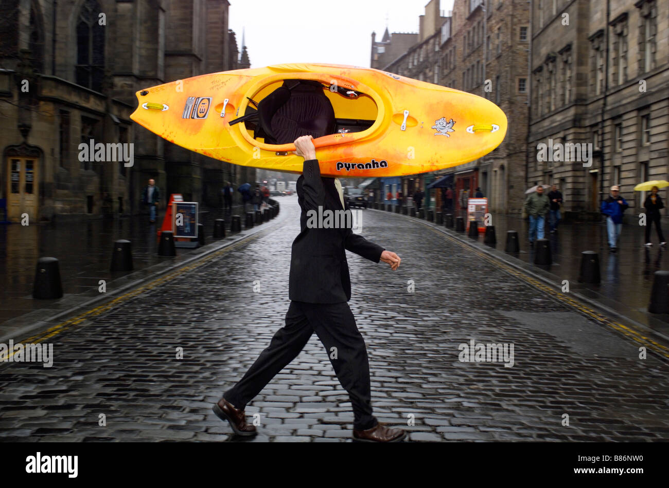 A man carrying a kayak across the road Stock Photo - Alamy