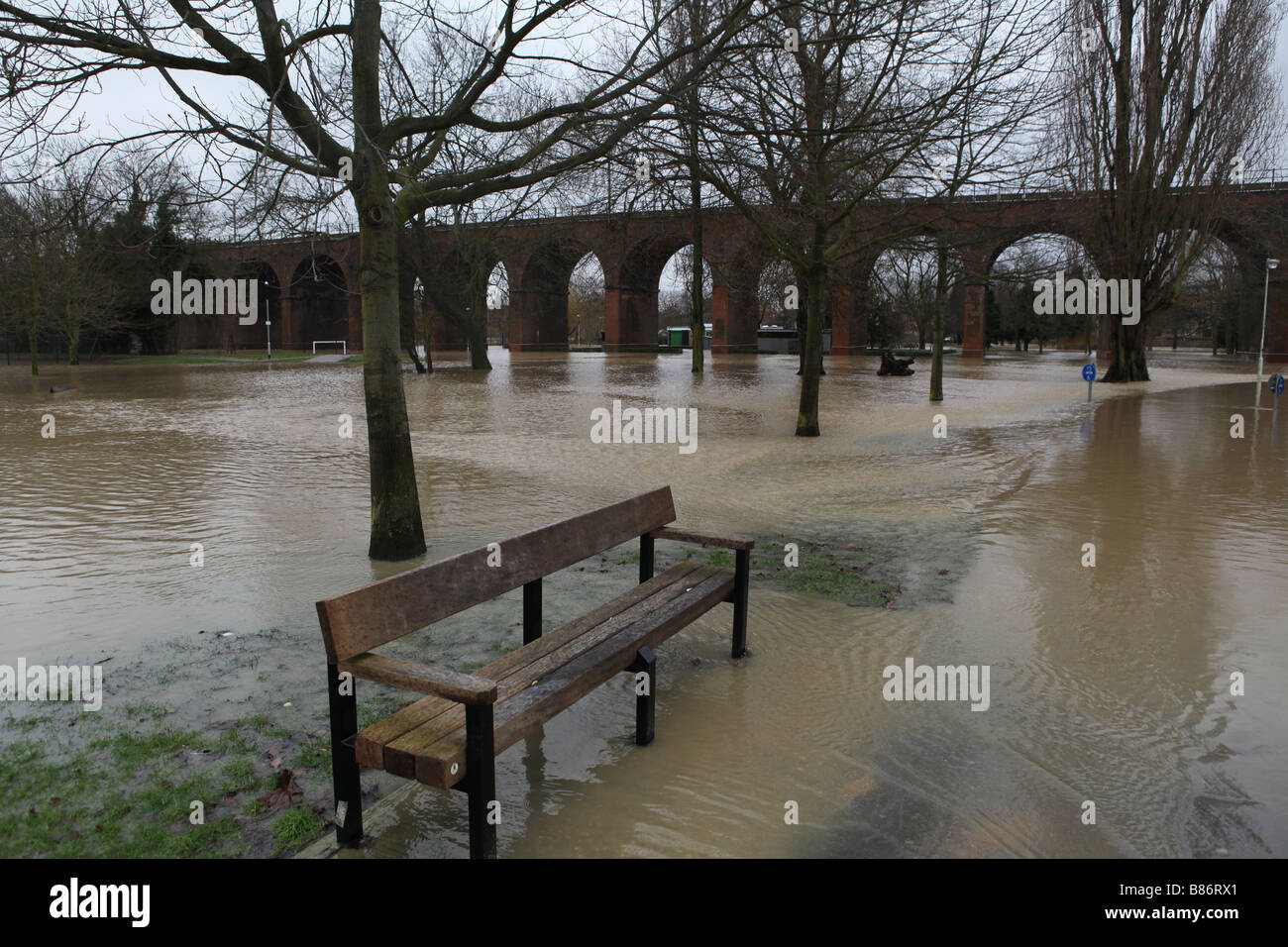 a park bench a tree and a bridge underwater due to flooding of the ...