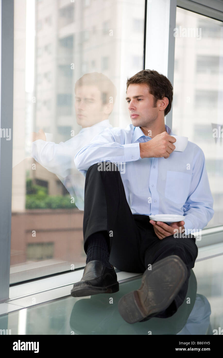 Businessman sitting by window looking out Stock Photo - Alamy