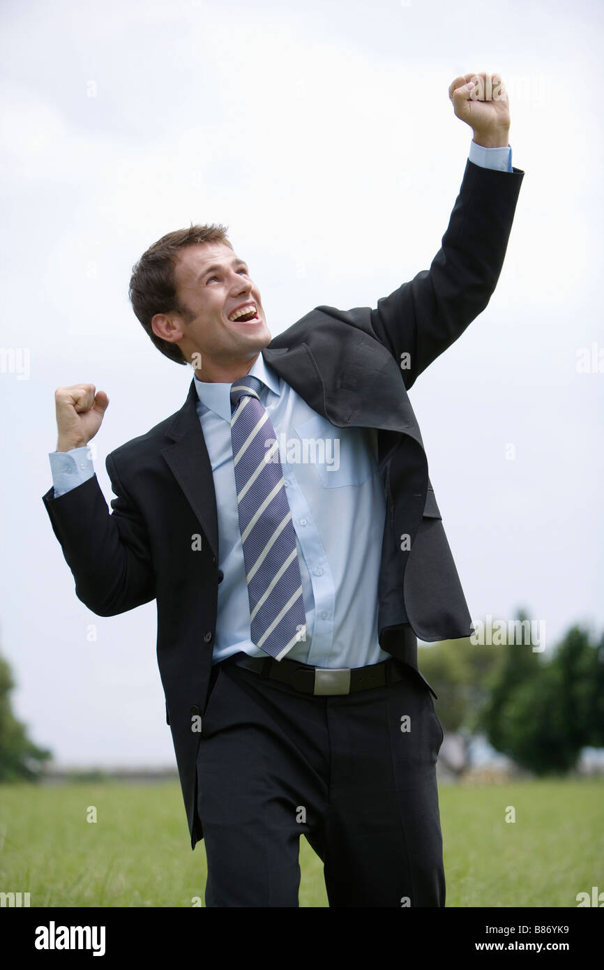 Businessman raising arms clenching fists smiling Stock Photo - Alamy