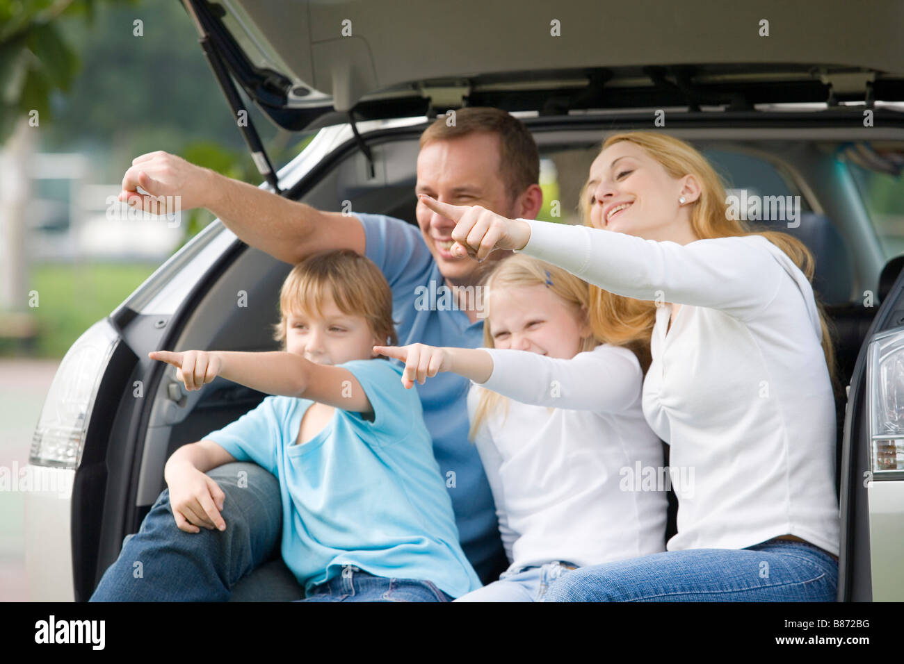 Family sitting in back of car pointing Stock Photo - Alamy