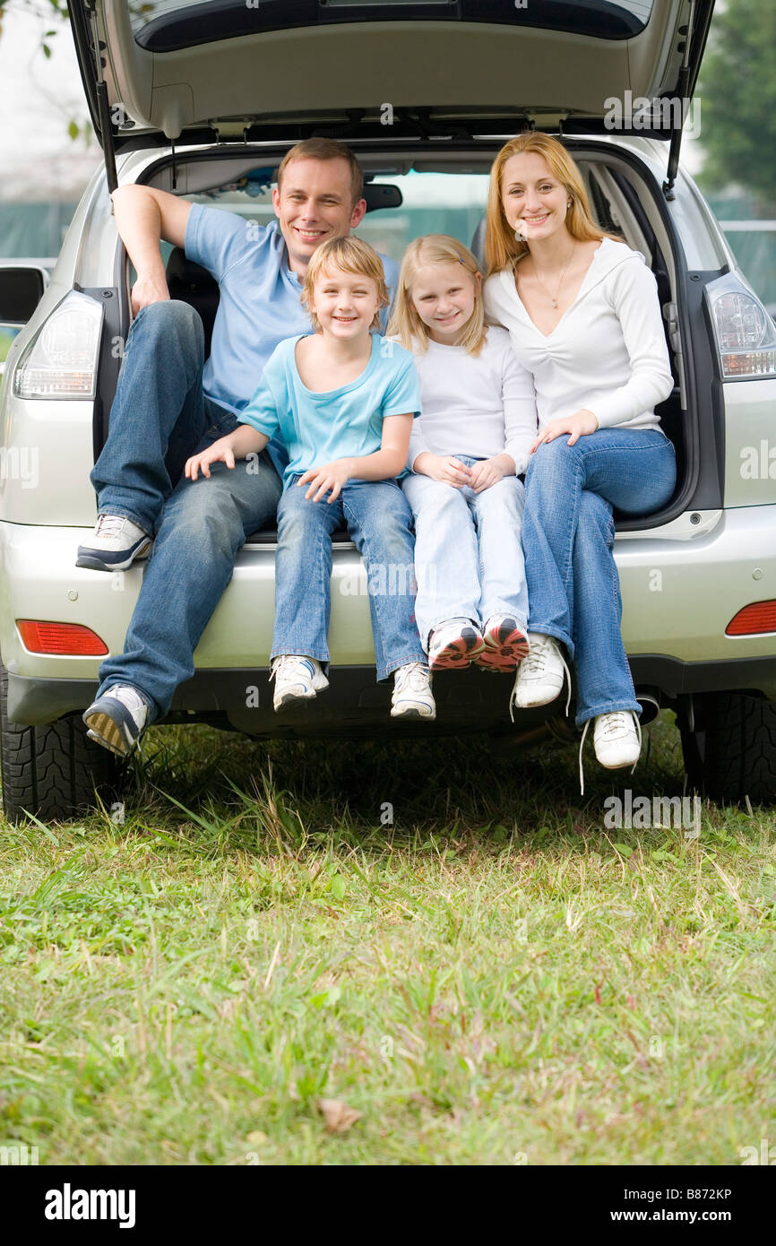 Family together sitting on rear of car portrait Stock Photo - Alamy