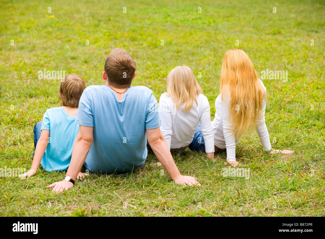 Family sitting on grass rear view Stock Photo - Alamy