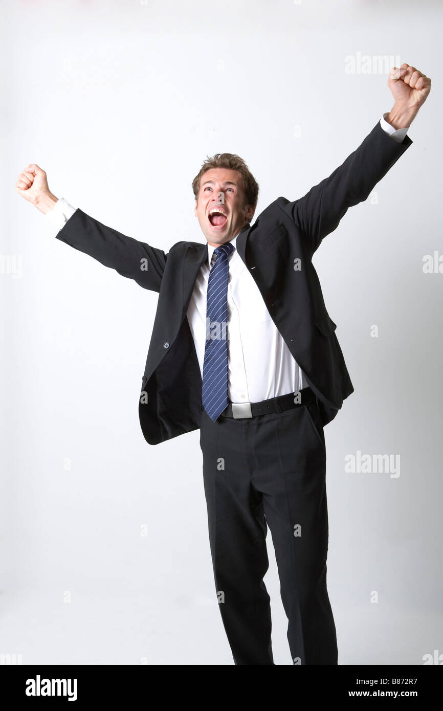 Businessman raising arms clenching fists smiling Stock Photo - Alamy