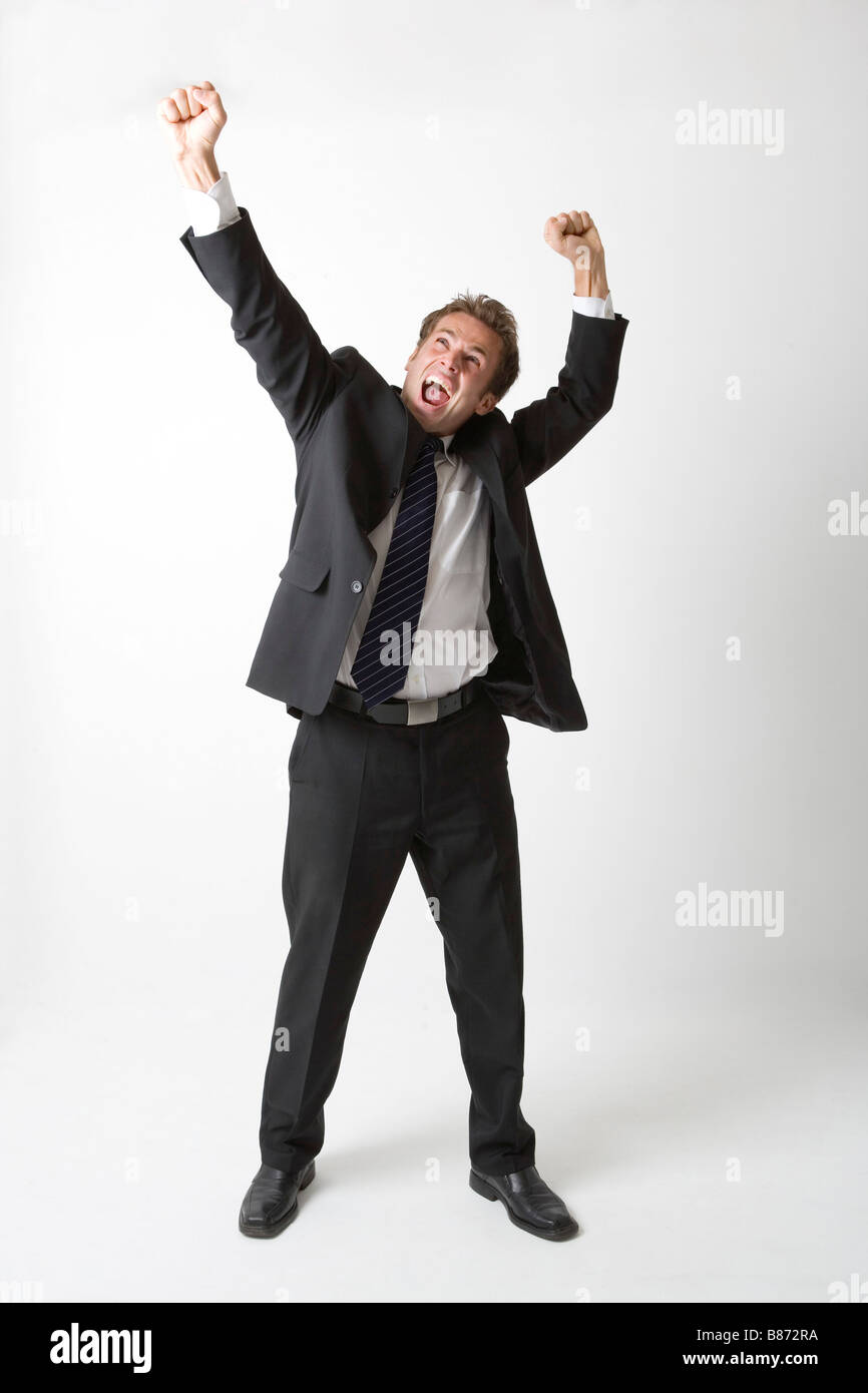 Businessman raising arms clenching fists smiling Stock Photo - Alamy