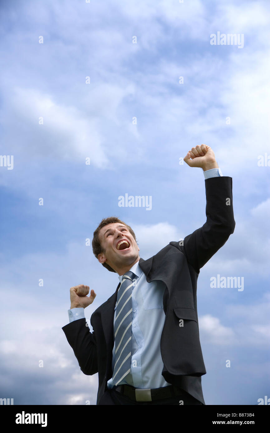 Businessman raising arms clenching fists smiling view from below Stock ...