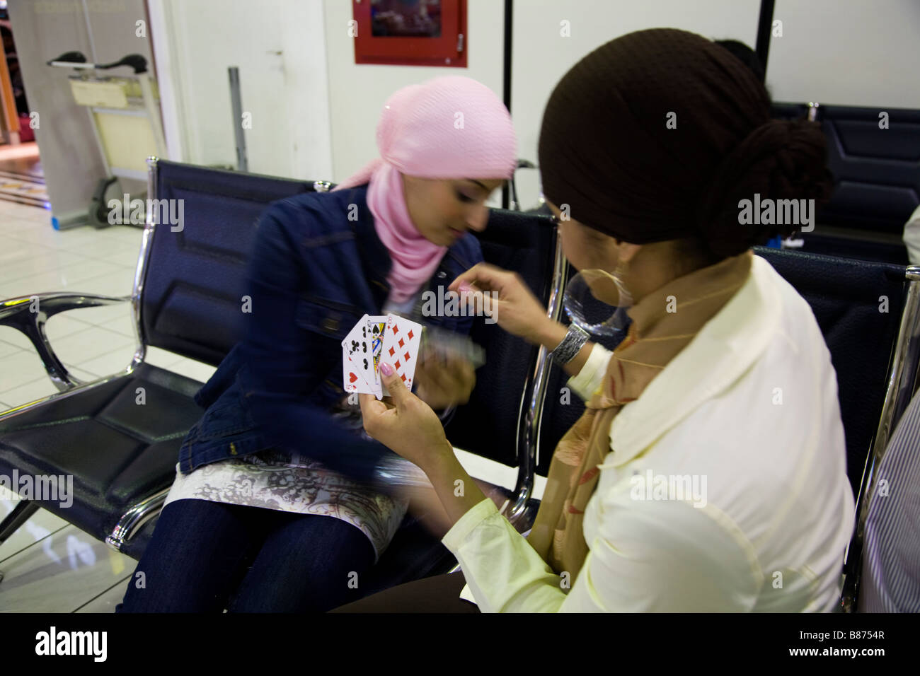 Young muslim women play cards in the departure lounge of Bahrain ...