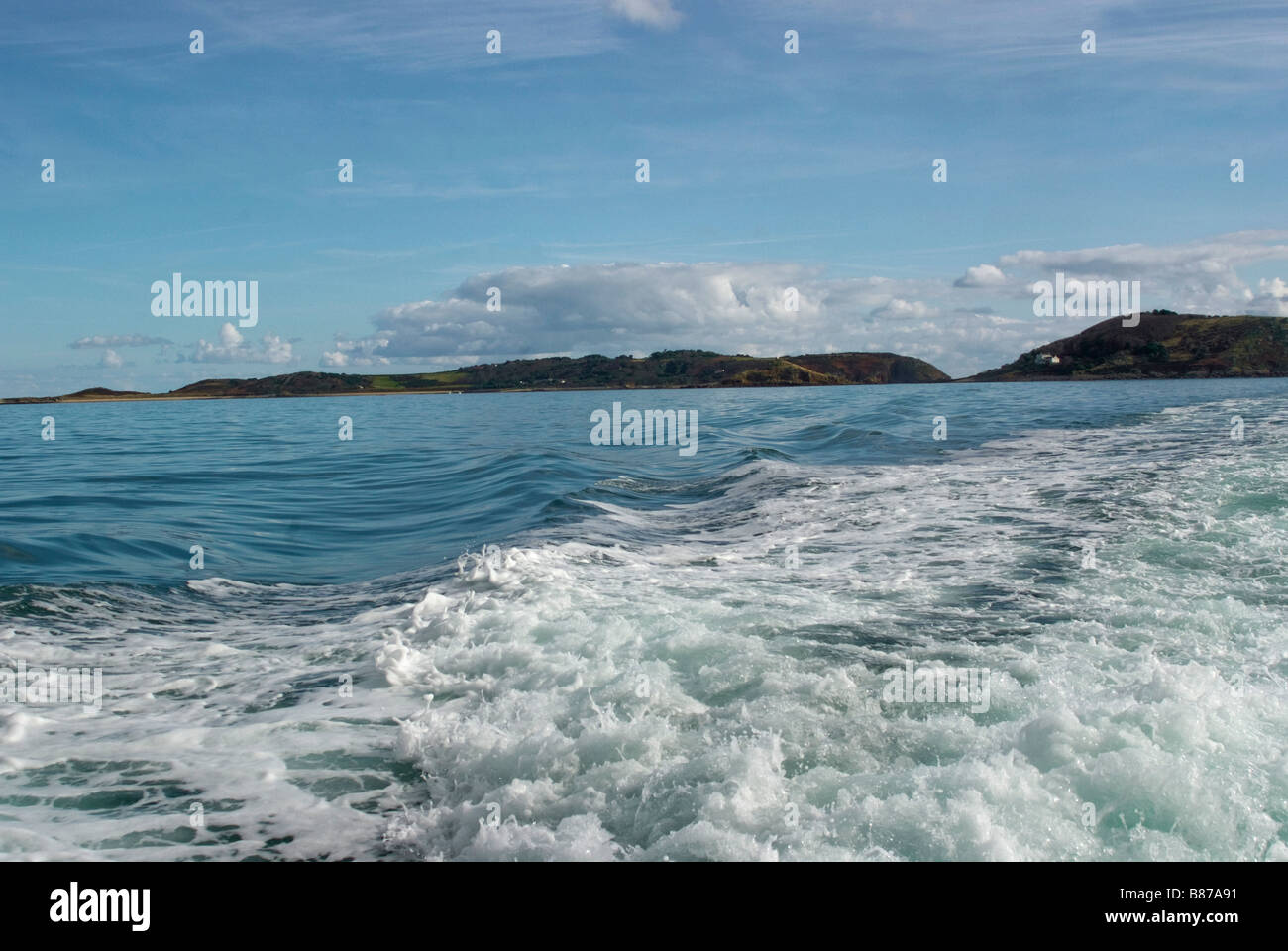 Looking back towards Herm and Jethou from a boat with the wake behind ...