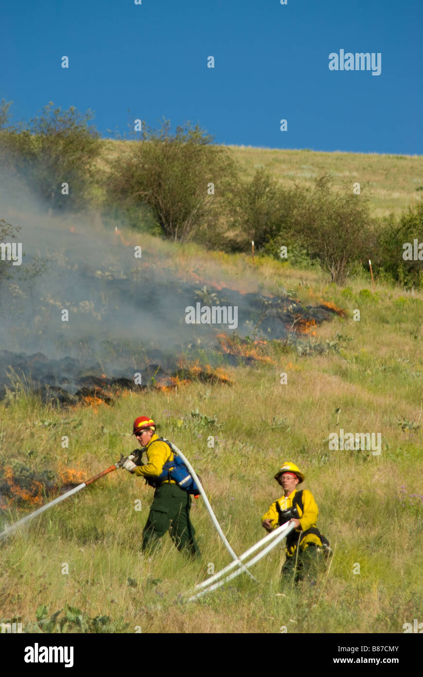 Fire fighters approaching a heavily smoking wild fire on a mountain ...