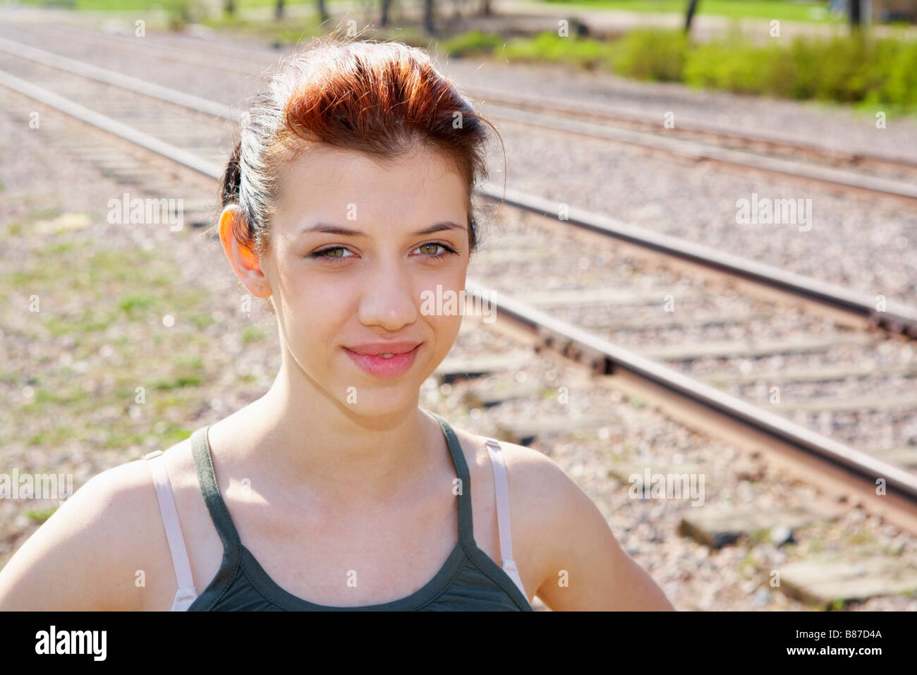 Teenage girl standing by railroad tracks Stock Photo - Alamy